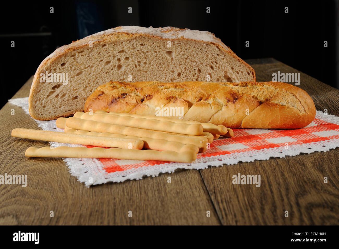 Several rustic loaves of bread warmly lit on a wood background Stock ...
