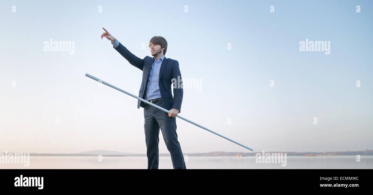 Handsome businessman holding long stick Stock Photo - Alamy