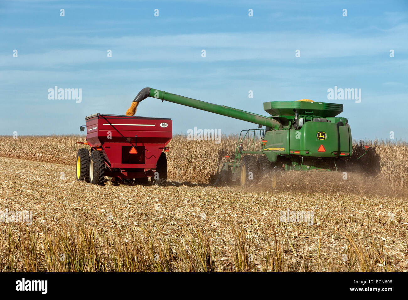 Farmer operating John Deere combine harvesting mature corn field Stock ...