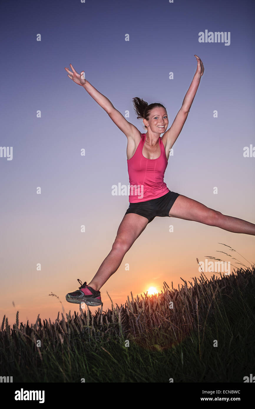 a young jumping woman in front of rural landscape and sunset Stock ...