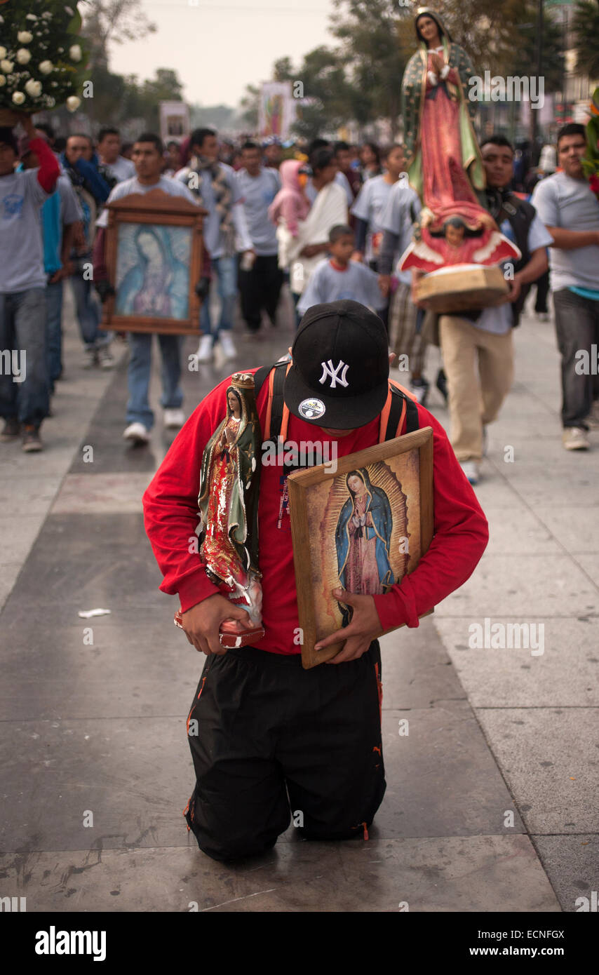 A pilgrim walks on his knees carrying images of the Virgin of Guadalupe ...
