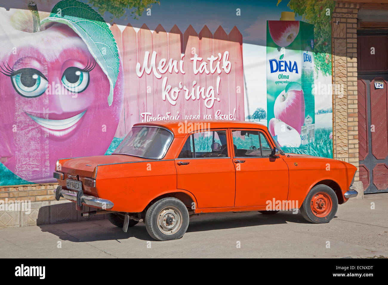 Old orange Trabant parked in front of advertisement painted on wall in ...