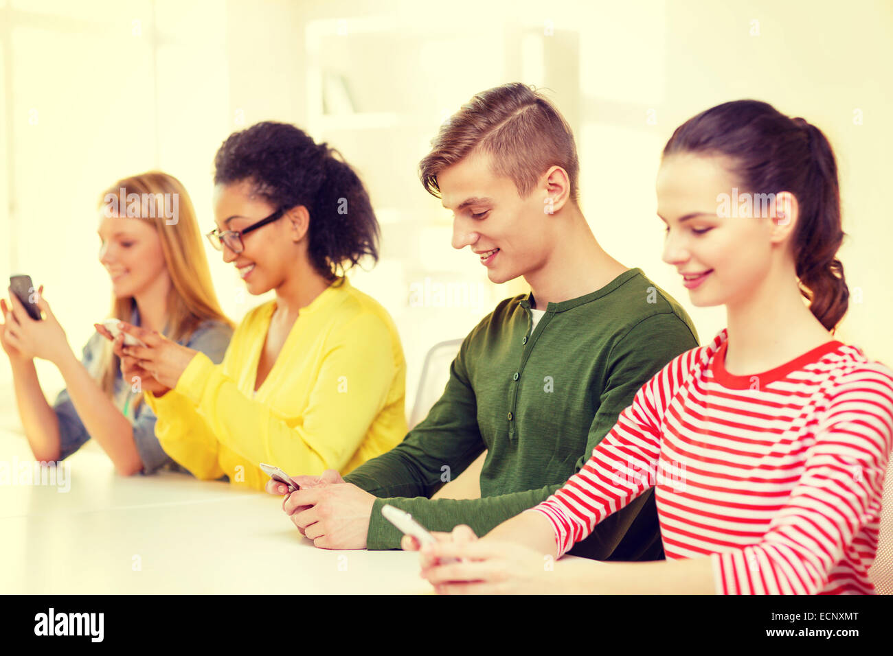 four smiling students with smartphones at school Stock Photo - Alamy