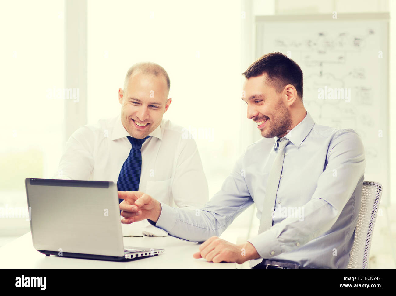 two smiling businessmen with laptop in office Stock Photo - Alamy