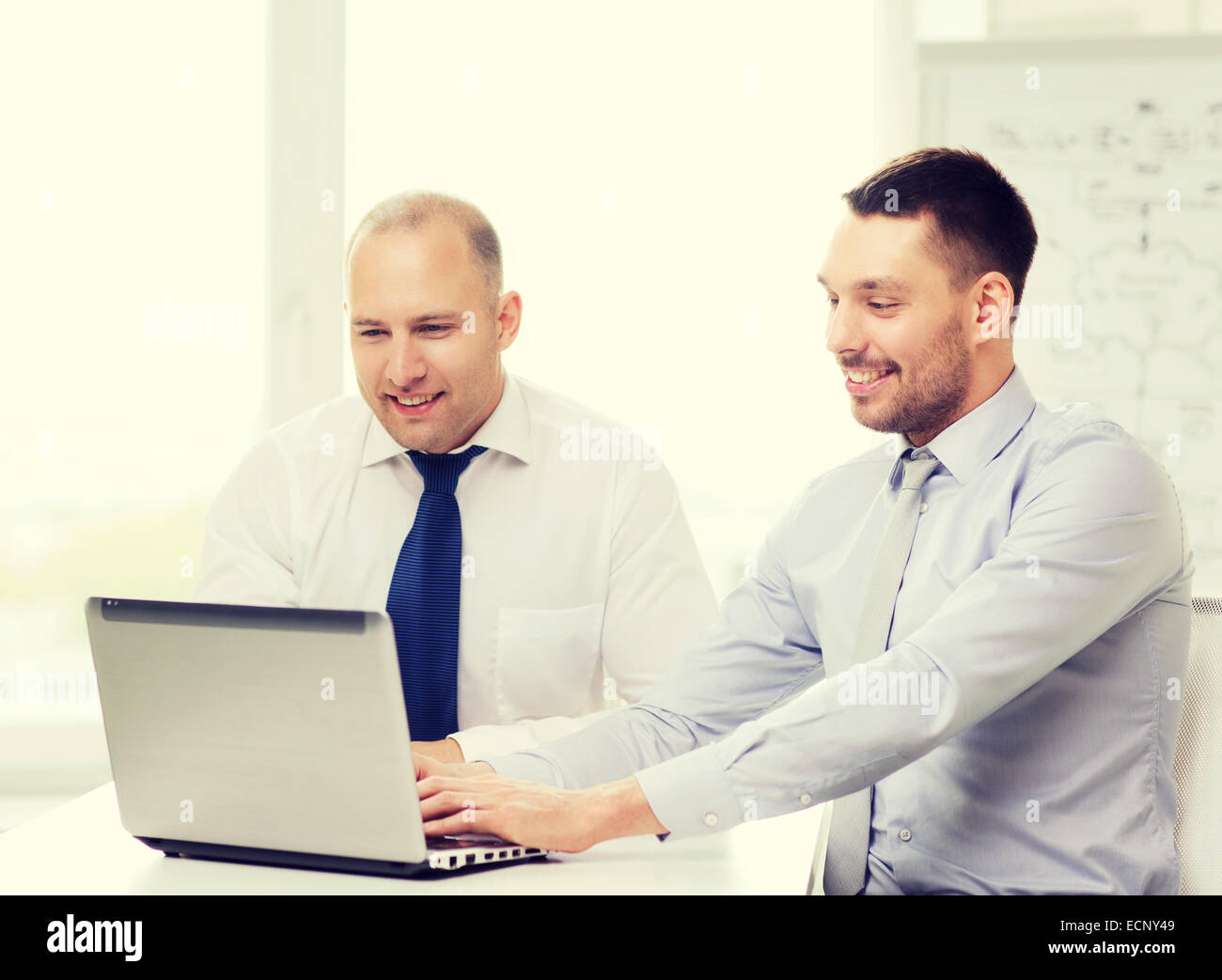 two smiling businessmen with laptop in office Stock Photo - Alamy
