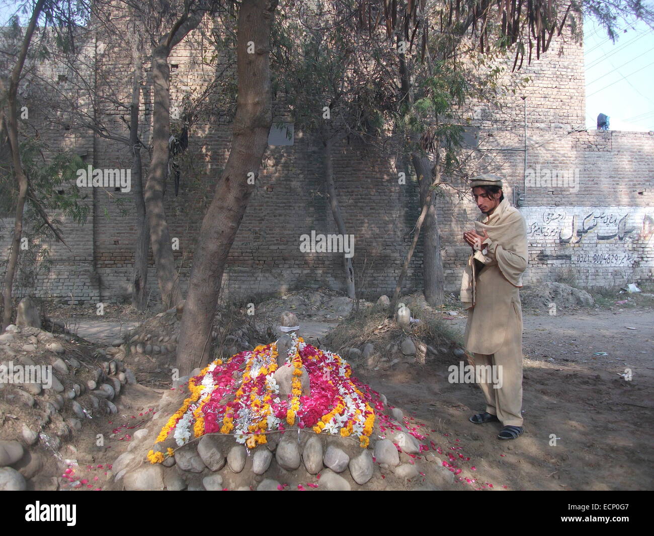 Peshawar, Pakistan. 17th Dec, 2014. A man grieves at the grave of 15 ...