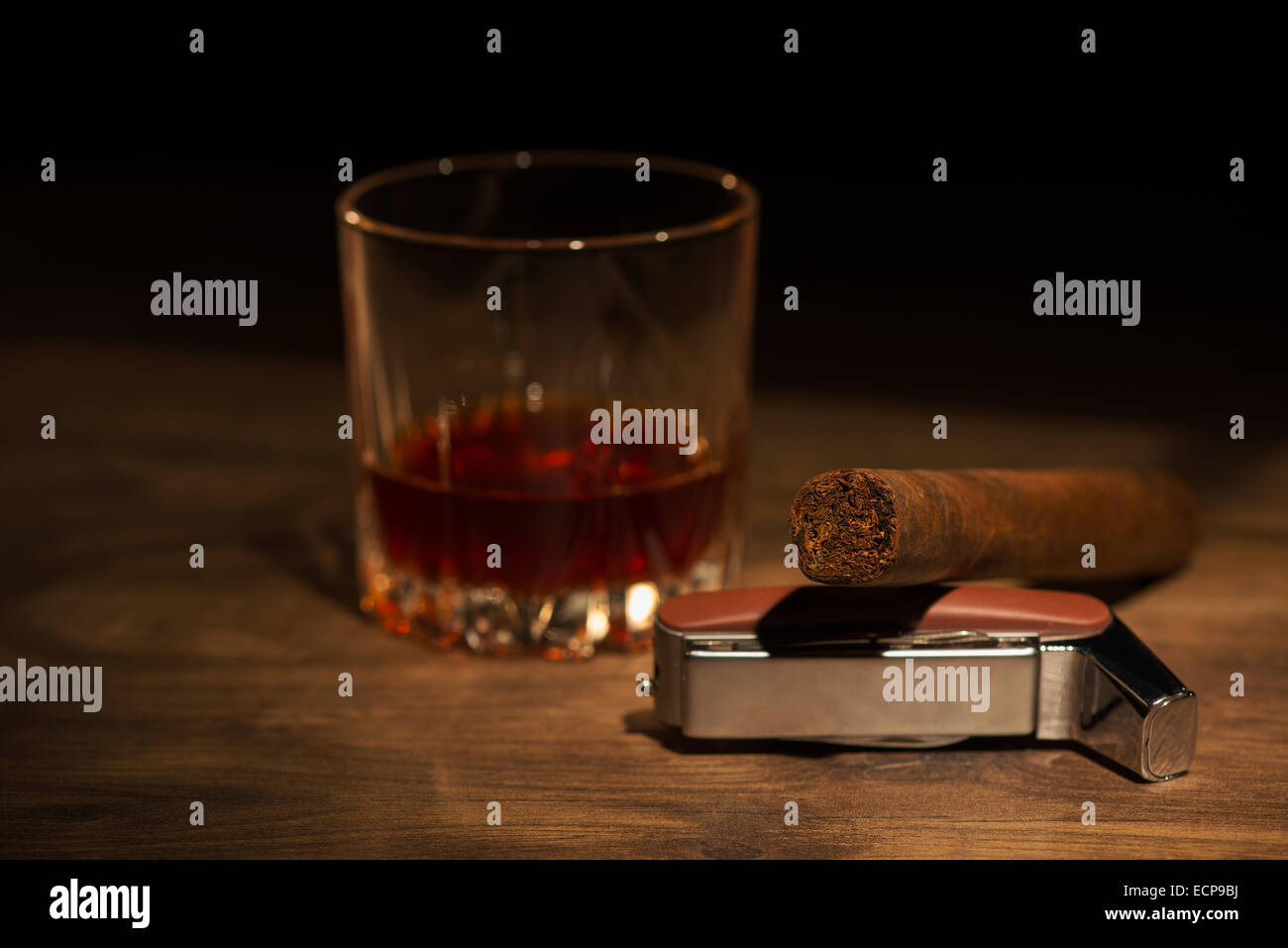 Selective focus on the Cuban cigar lying on the lighter near the glass ...