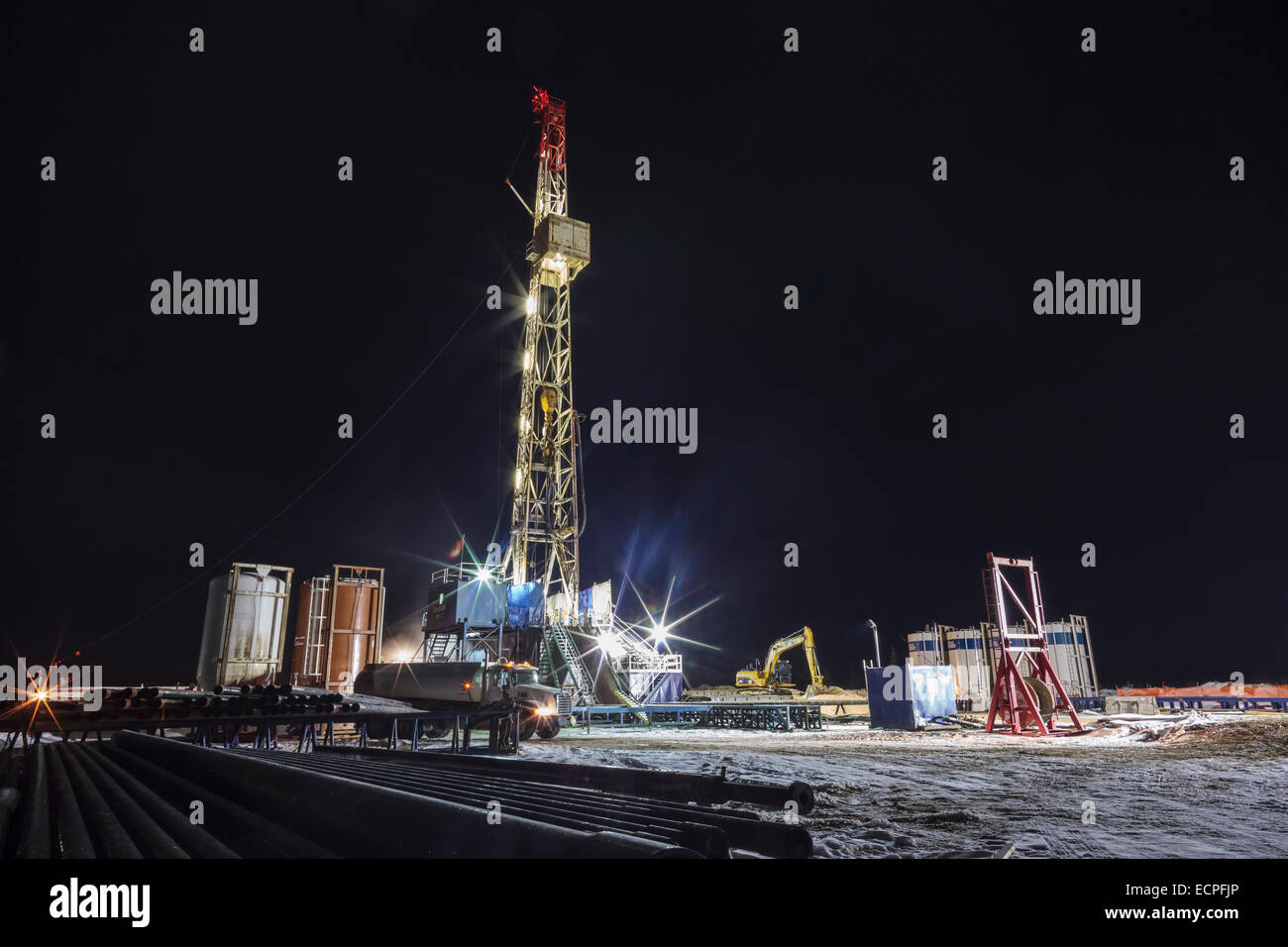 A drilling rig extracting natural gas operates through the night near ...