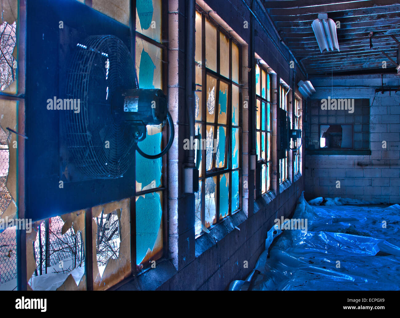 Industrial fans and broken windows at an abandoned warehouse building ...