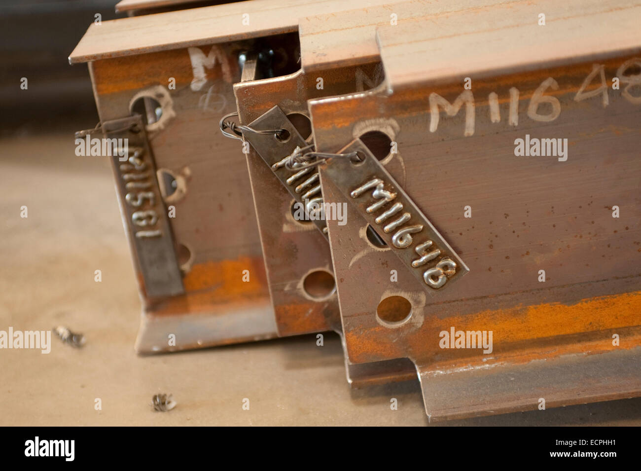 Three structural steel beams with part numbers and tags sitting on a ...