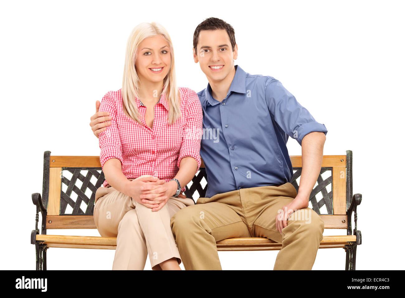 Cheerful young couple posing seated on a bench isolated on white ...