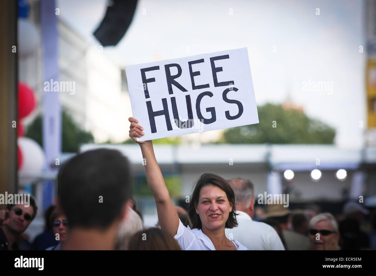 a young woman holding up a sign and offering Free Hugs for everybody ...