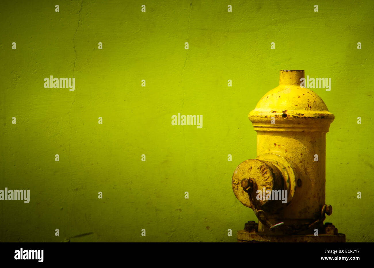 Yellow fire hydrant against a green background Stock Photo - Alamy
