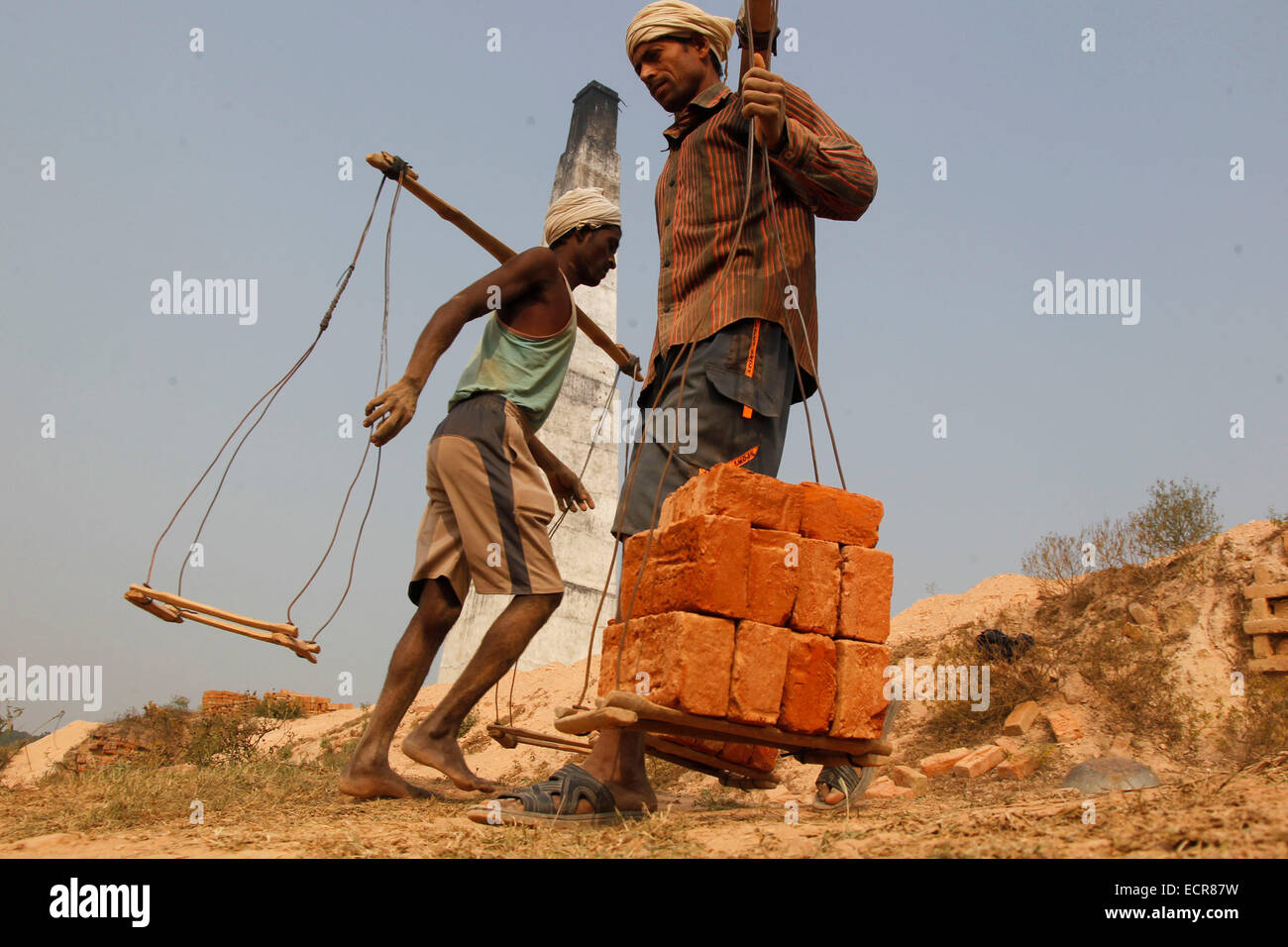 Laborer carries bricks to be properly piled inside the factory on fogy ...