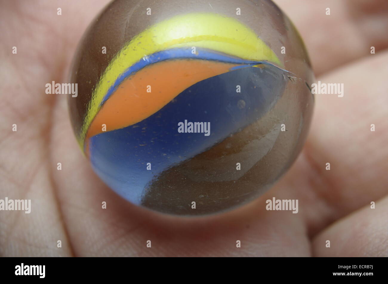 Close up of a glass marble in child 's hand for playing shoot marbles ...