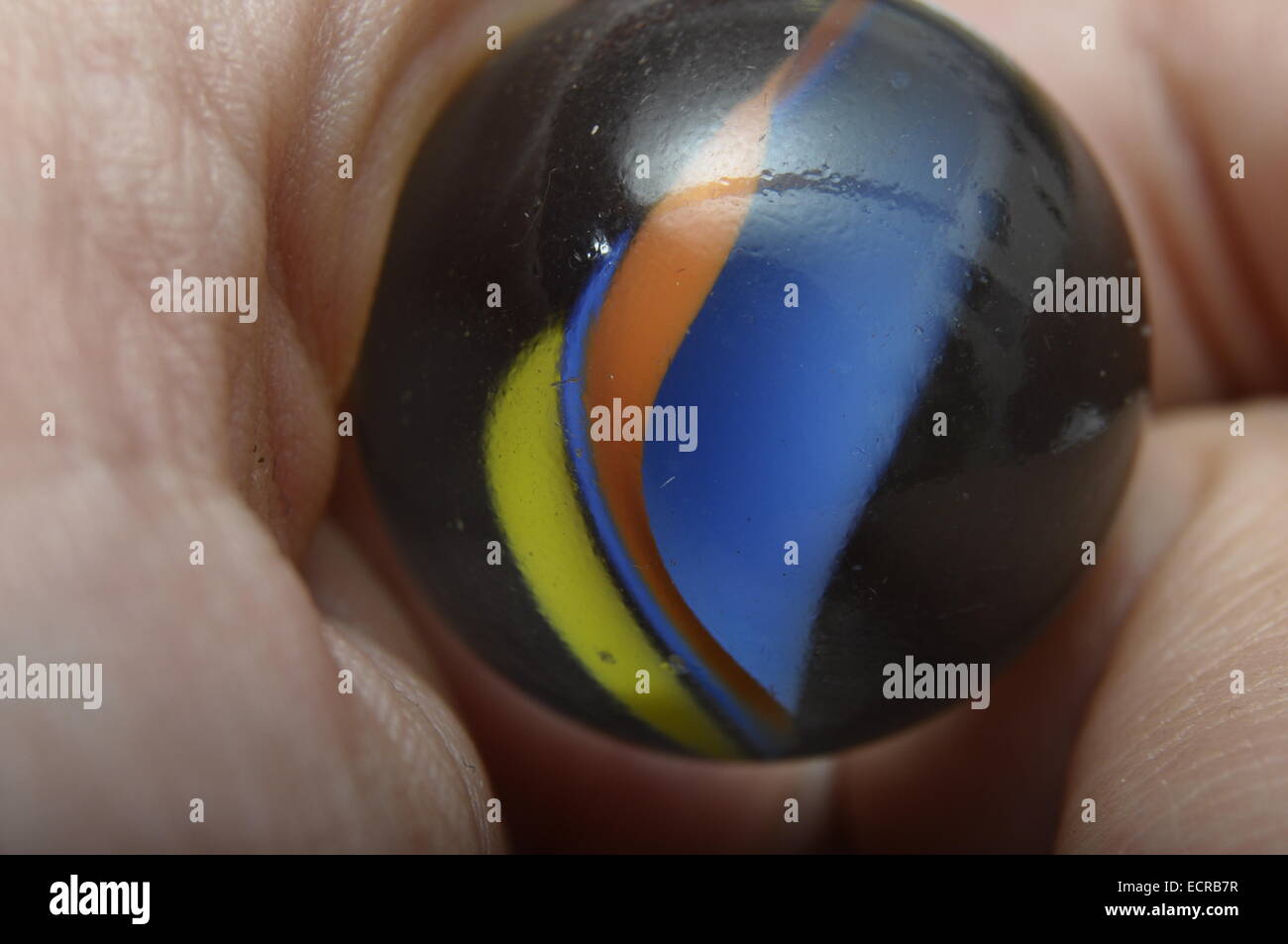 Close up of a glass marble in child 's hand for playing shoot marbles ...