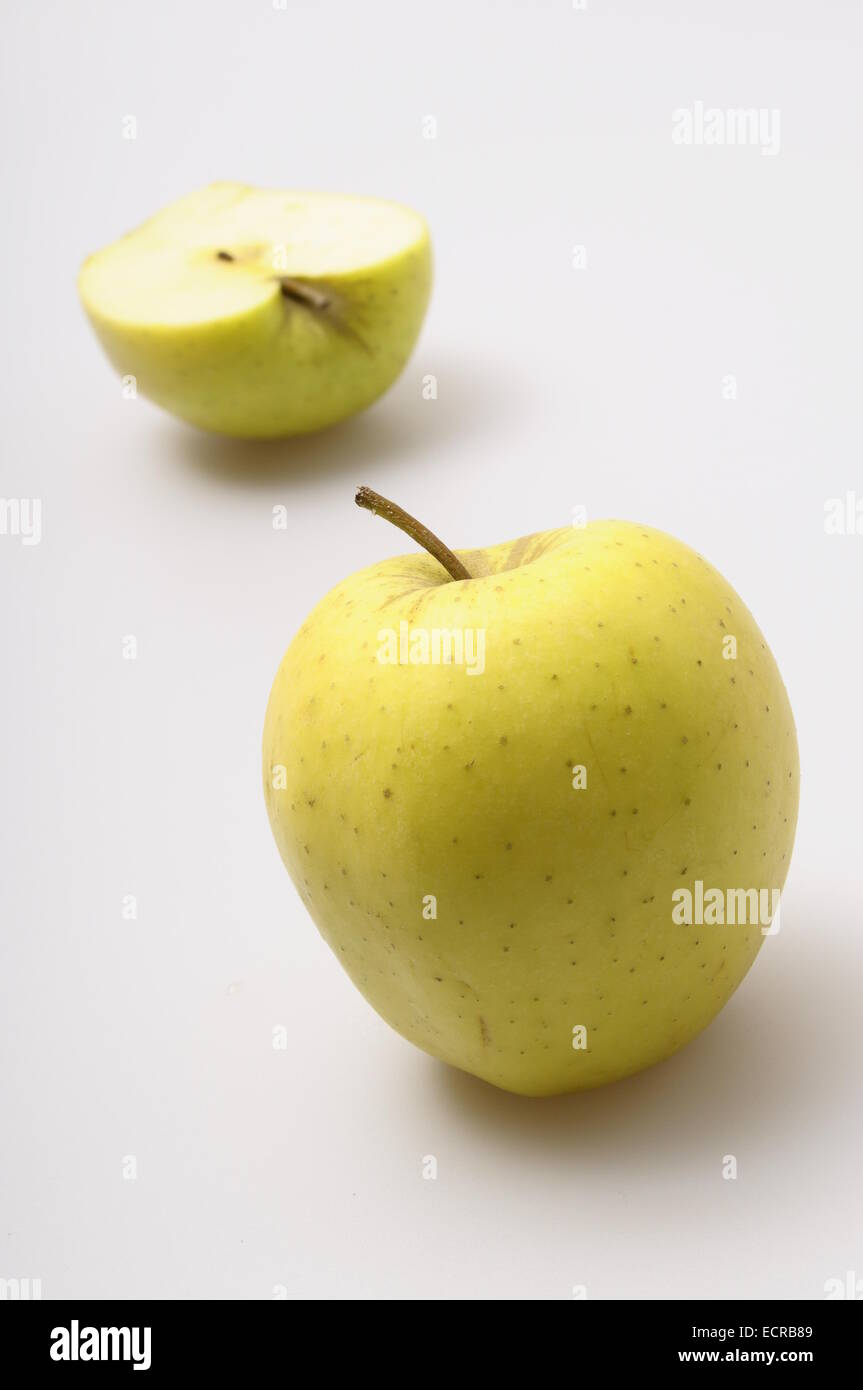 Two yellow golden apples on light background, one cut and opened ready ...