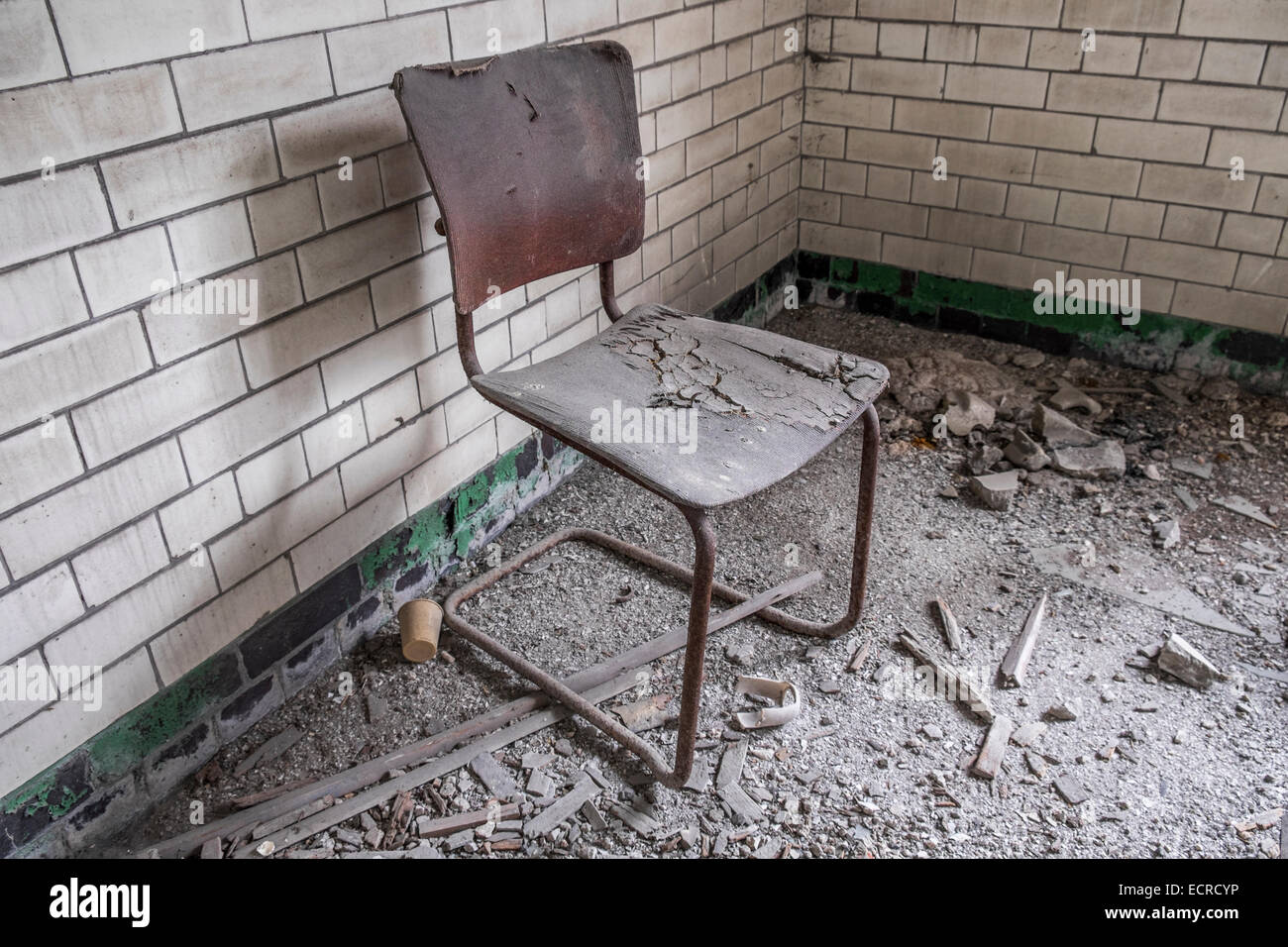 an old chair in a white tiled room where the tiles are very dirty and ...