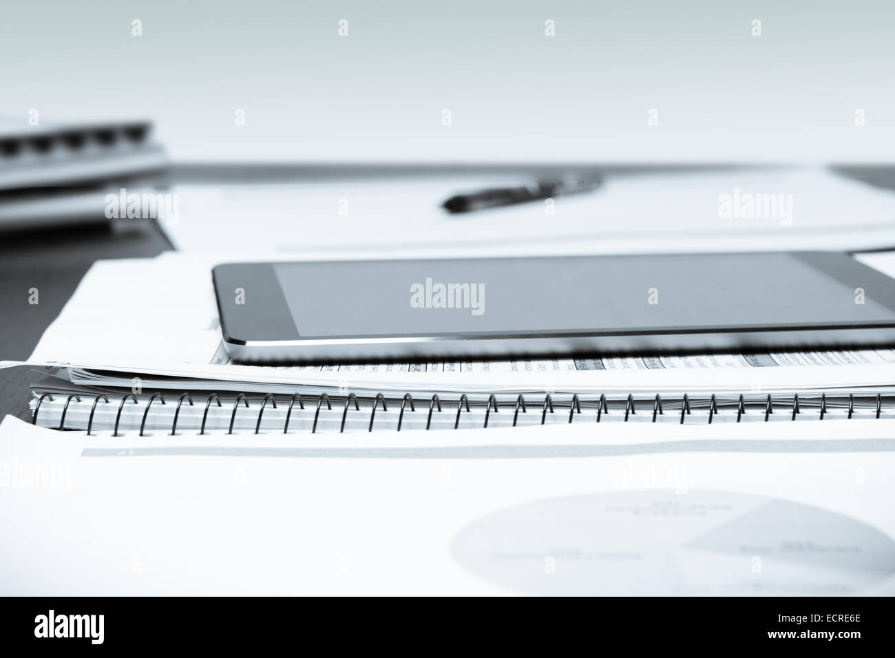 A tablet PC on an office desk. There are spreadsheets on white computer ...