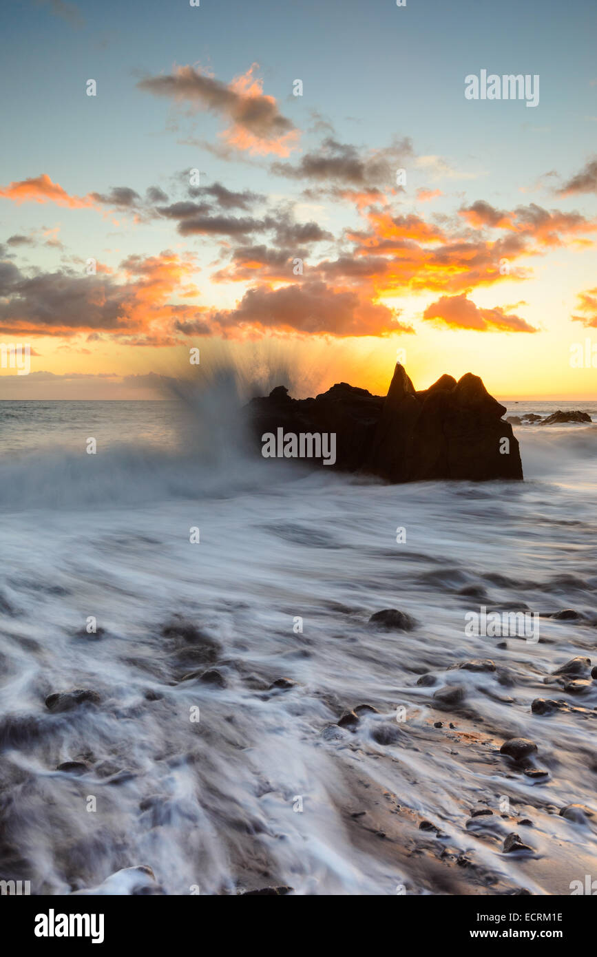 Waves crashing against a rock in the ocean at sunset Stock Photo - Alamy