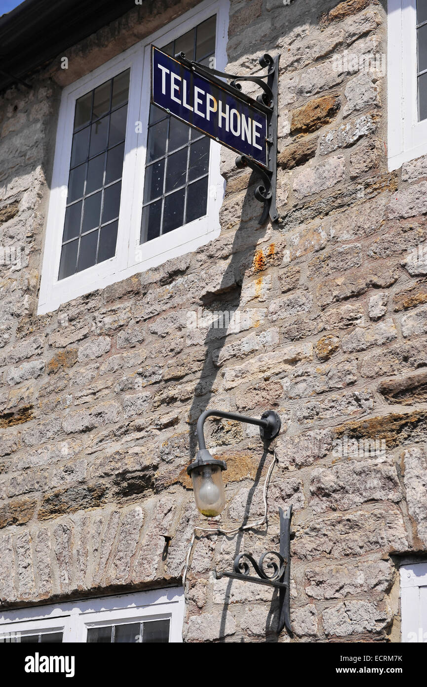 A vintage telephone sign on a building in Corfe Castle Village, Dorset ...