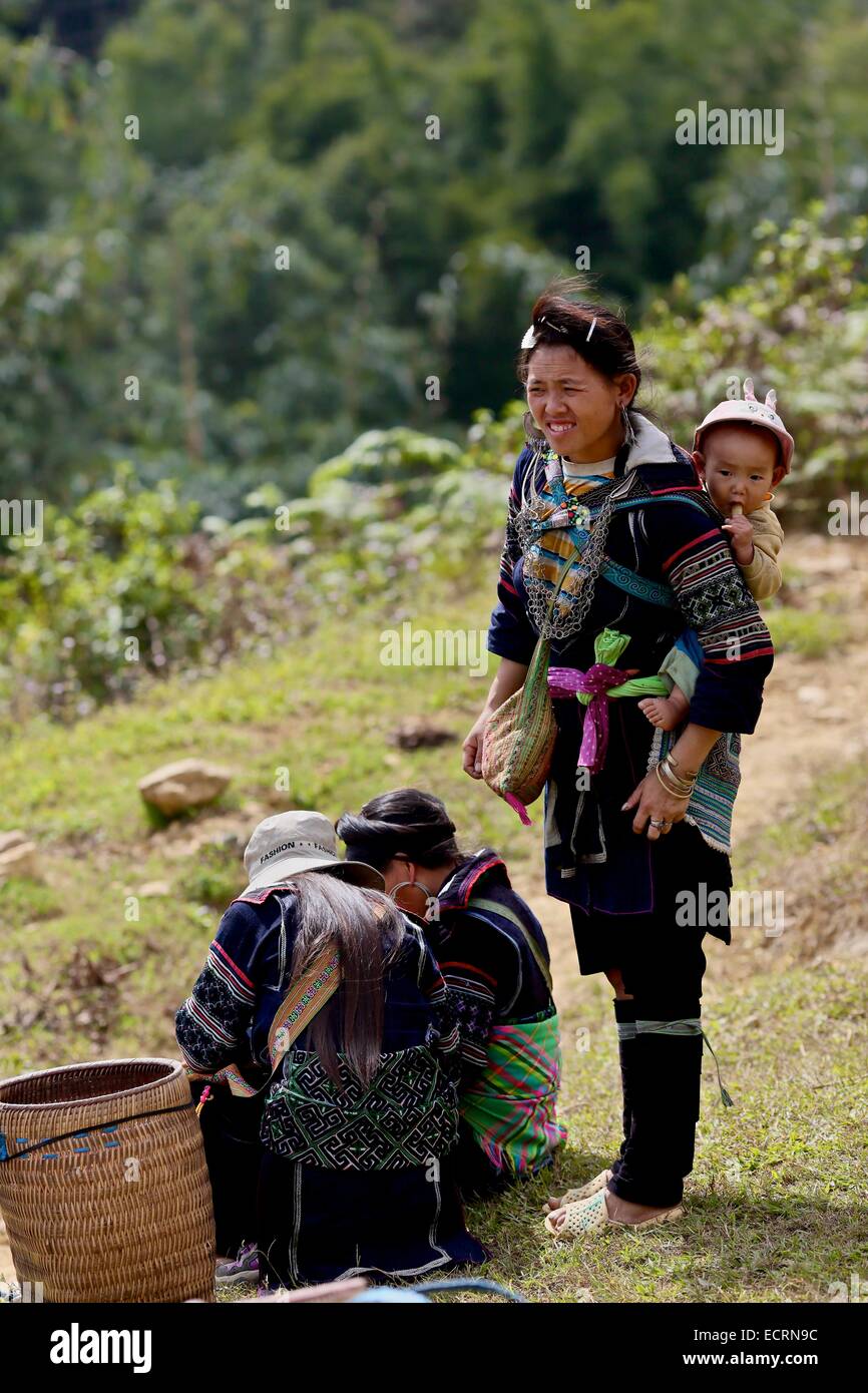 Hmong women, one with a young child, rest on their way to market at ...