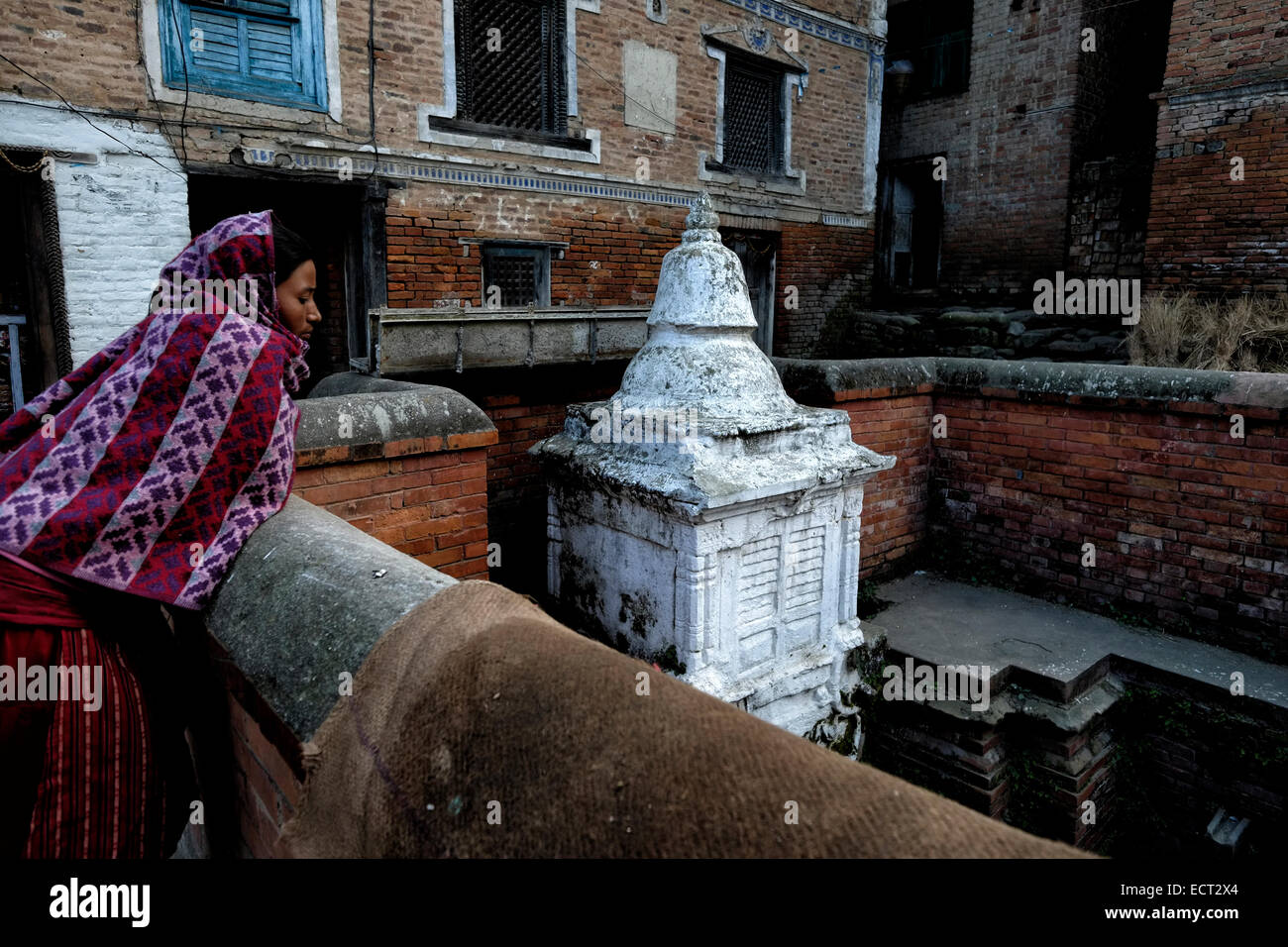 A Nepali woman stands over the brick-lined water tank of the Dey Pukha ...