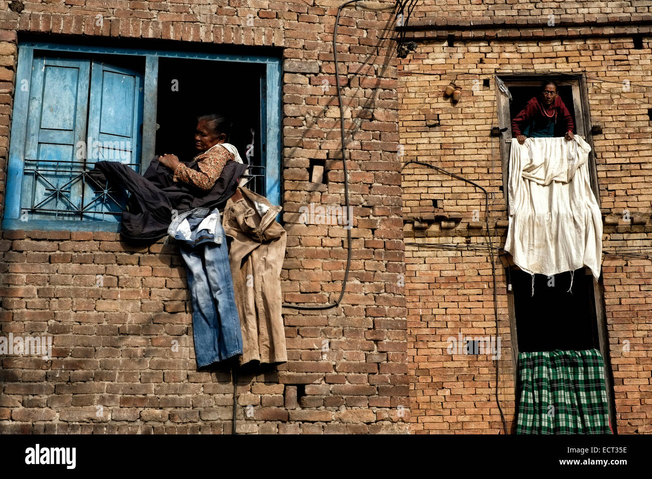 A woman peers out the window of a house in a residential building in ...