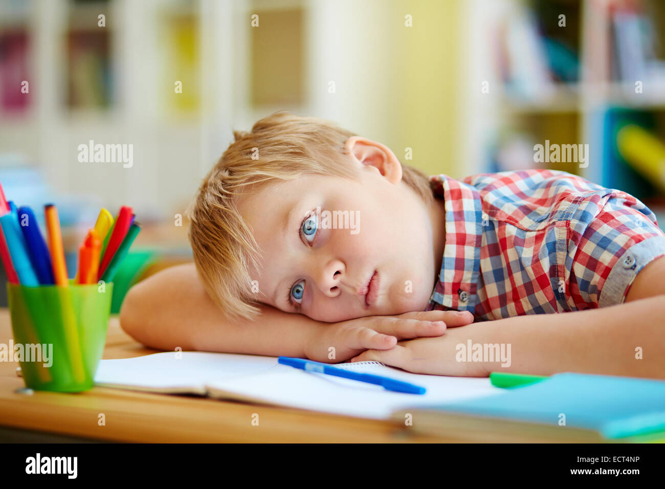 Bored or pensive schoolboy lying on desk Stock Photo - Alamy