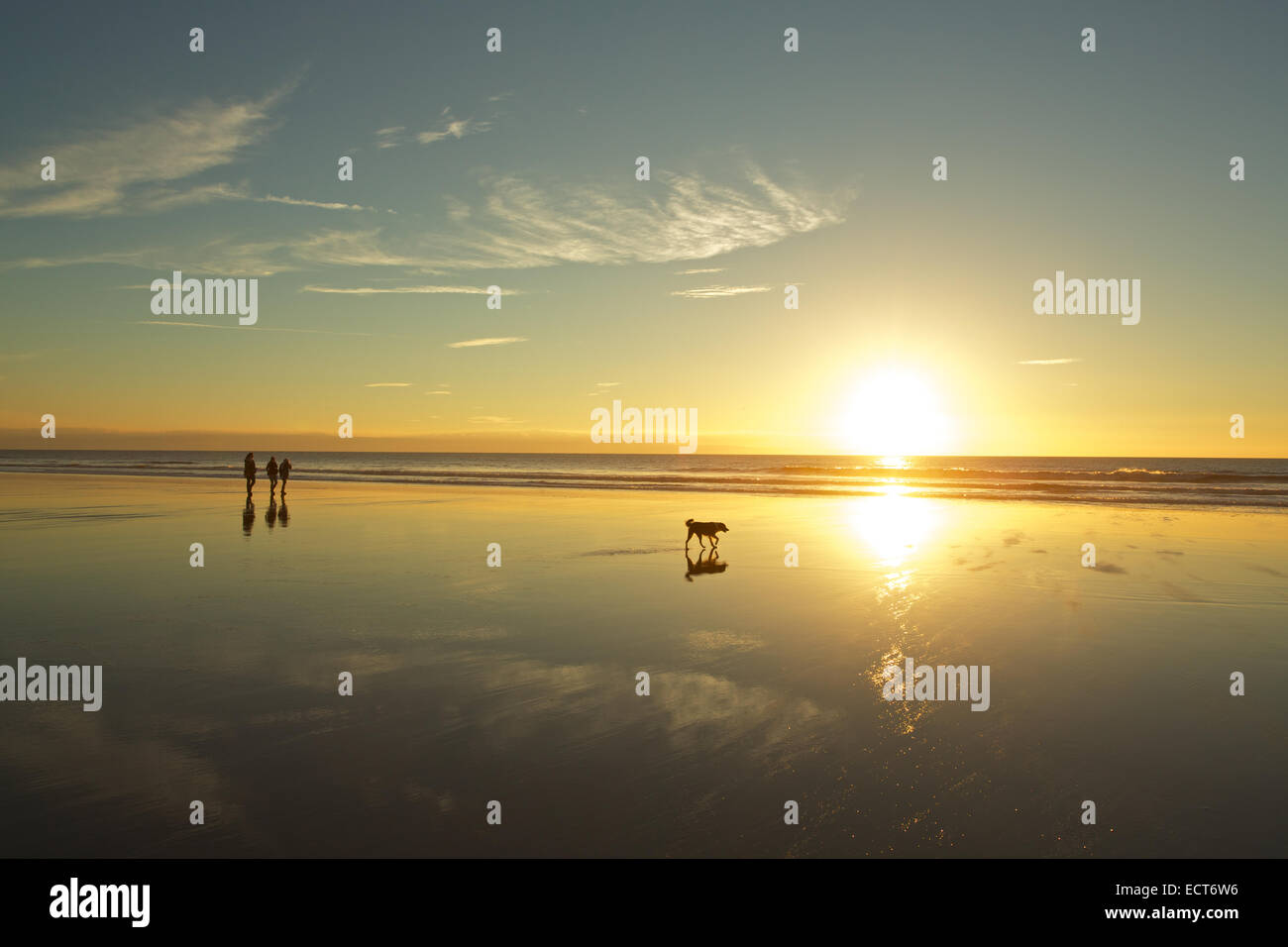 Walkers and dog walk on empty beach during autumn evening, Monknash ...