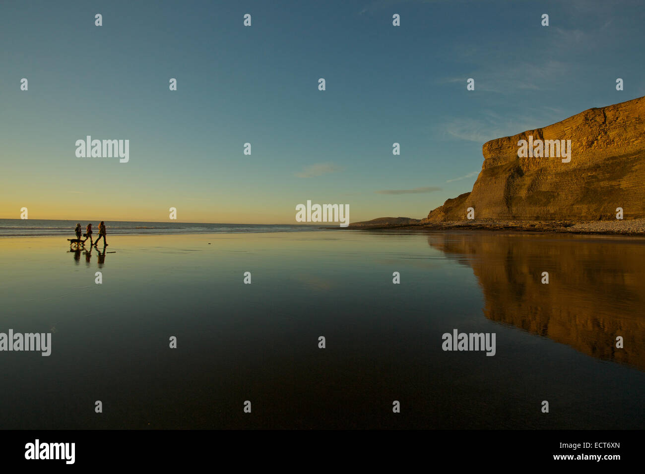 Walkers and dog walk on empty beach during autumn evening, Monknash ...