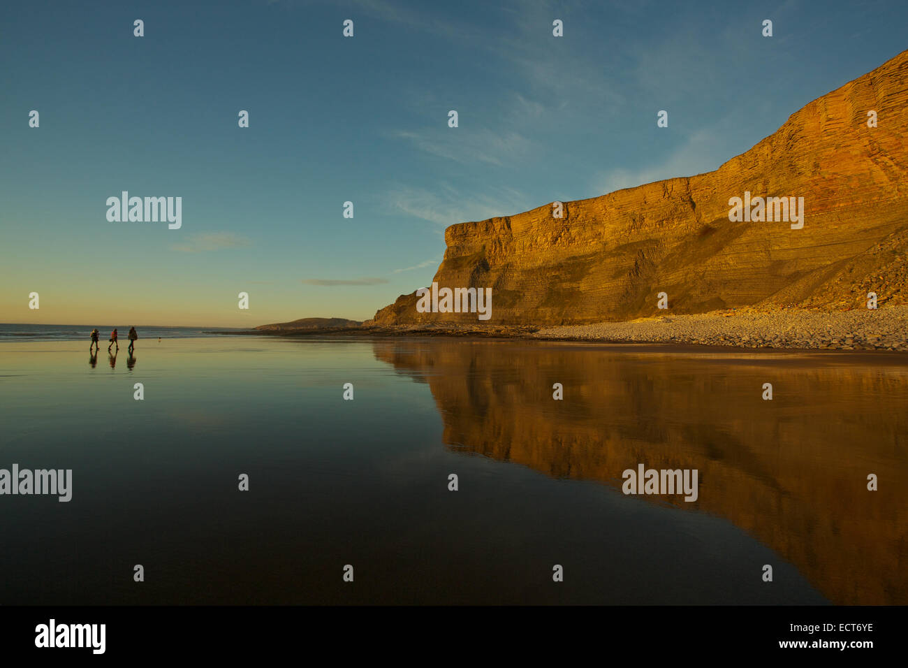 Walkers and dog walk on empty beach during autumn evening, Monknash ...