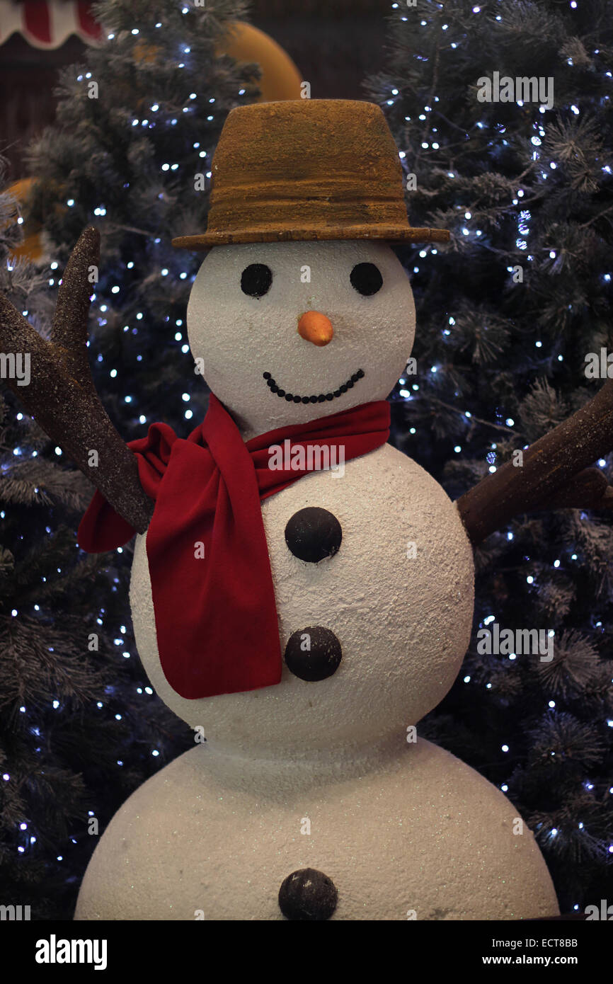 A Christmas decorative snowman wearing a scarf with a tree behind Stock ...