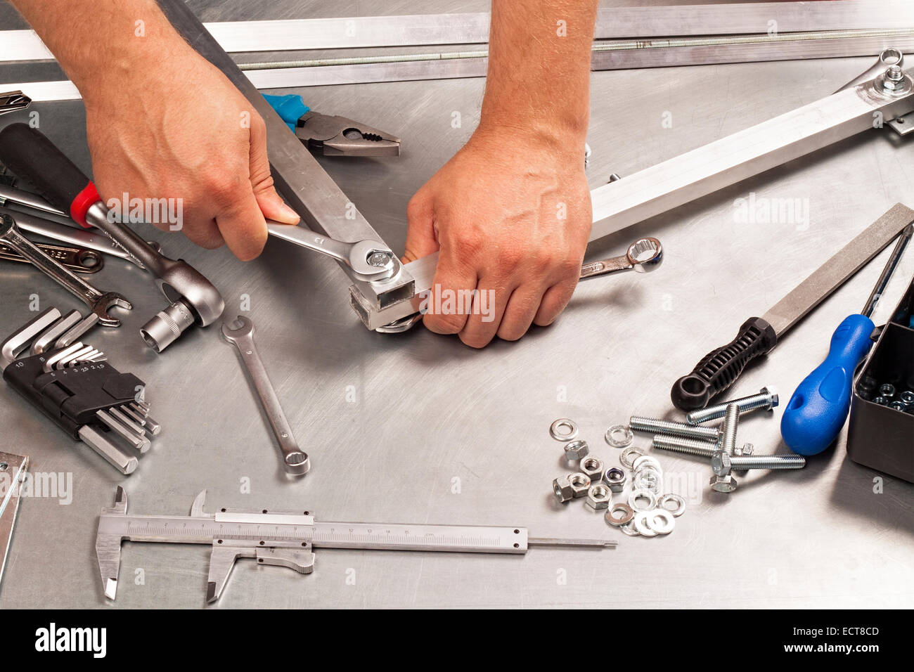Metal workshop table and some tools, hands fixing two rectangle rods ...