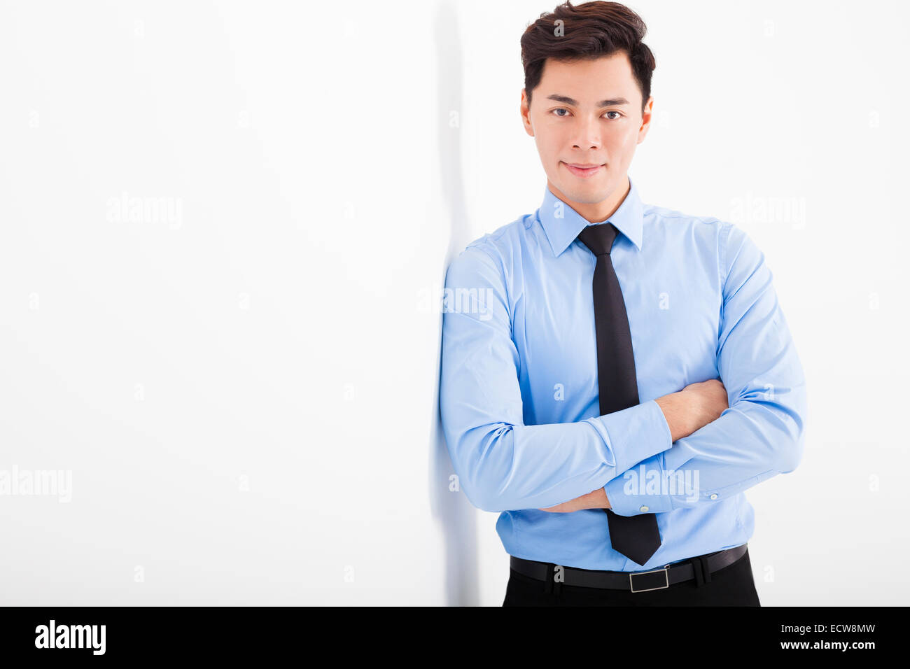 young businessman leaning against white wall in office Stock Photo - Alamy