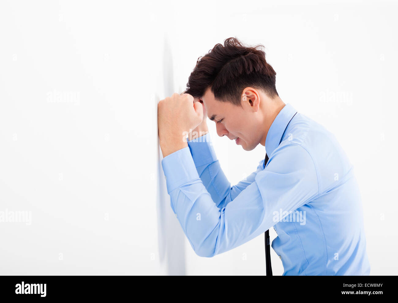 depressed young business man leaning at the wall in office Stock Photo ...