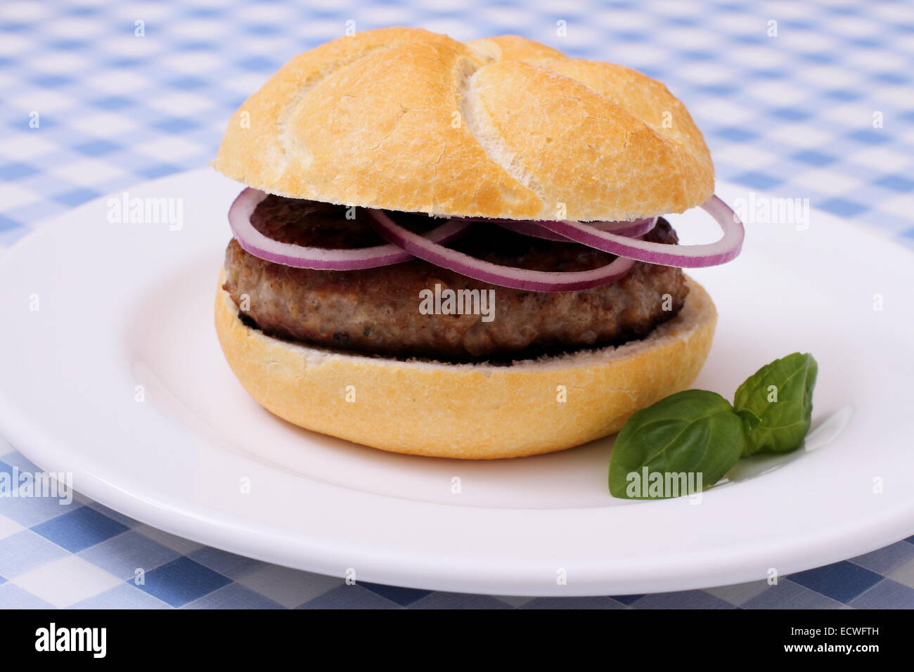 German Hamburger on plate, white blue checkered tablecloths, close up ...