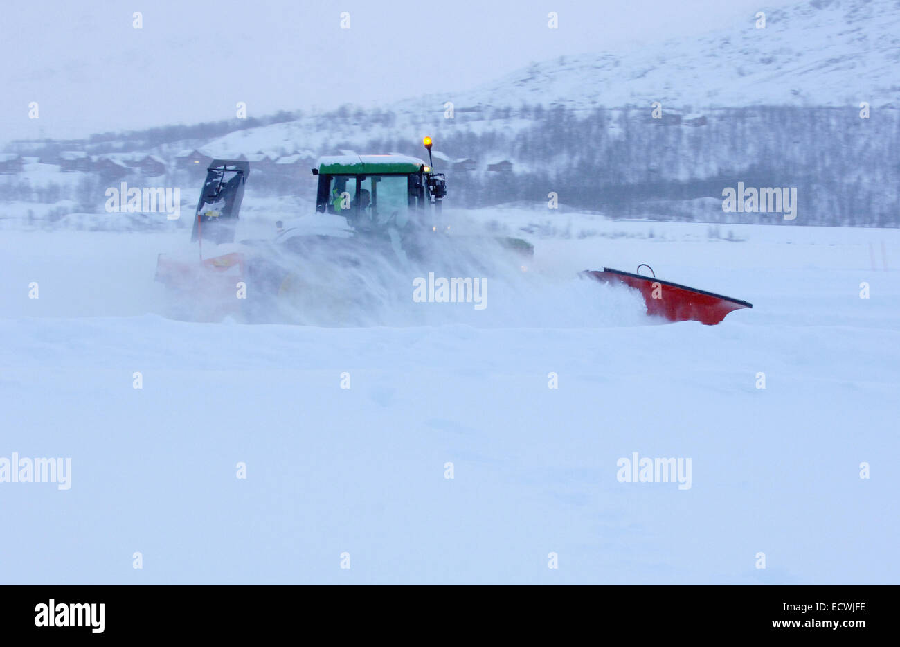Snow plough tractor driving on snow and ice clearing a road near the ...