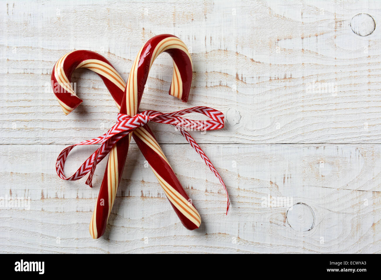 Closeup of two old fashioned candy canes on a rustic whitewashed wooden ...