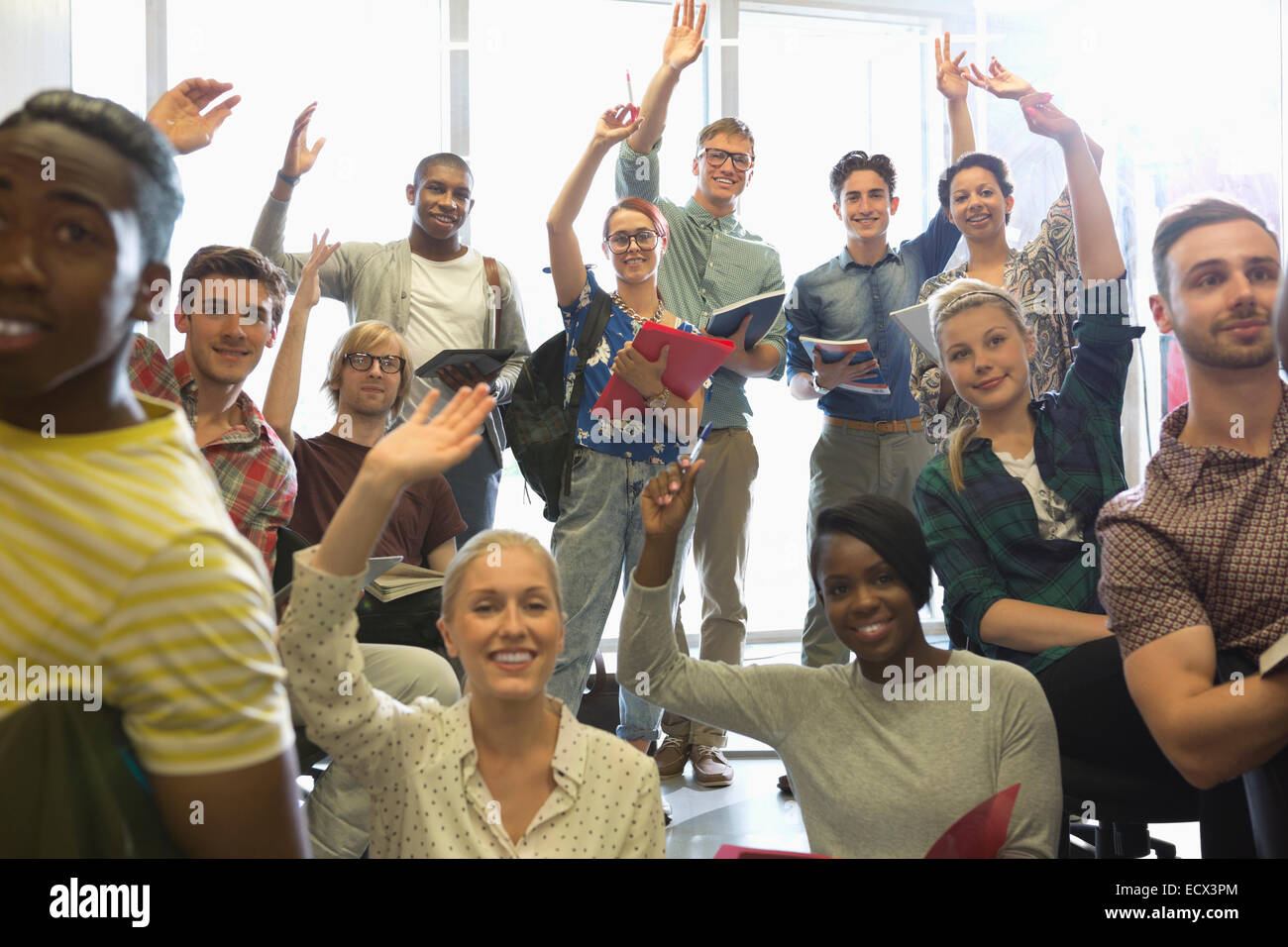 Smiling university students raising their hands at seminar Stock Photo ...