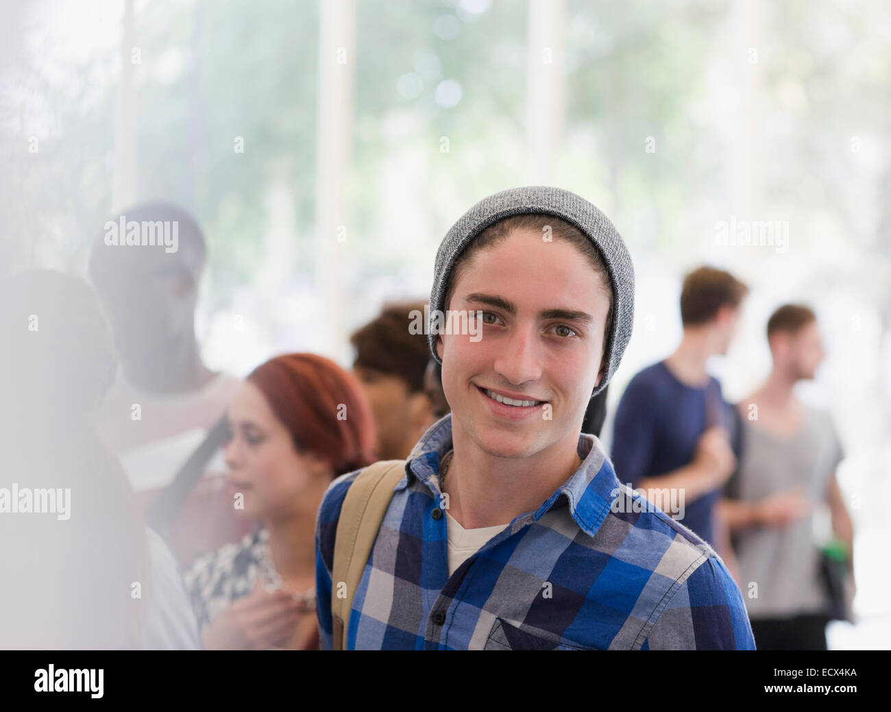 Portrait of smiling university student during break, people talking in ...