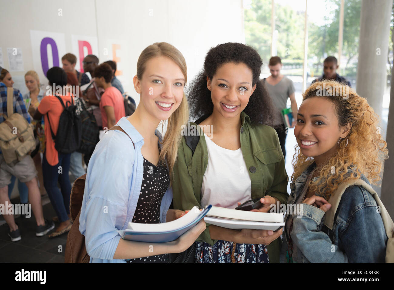 Portrait of university friends standing in corridor with books Stock ...