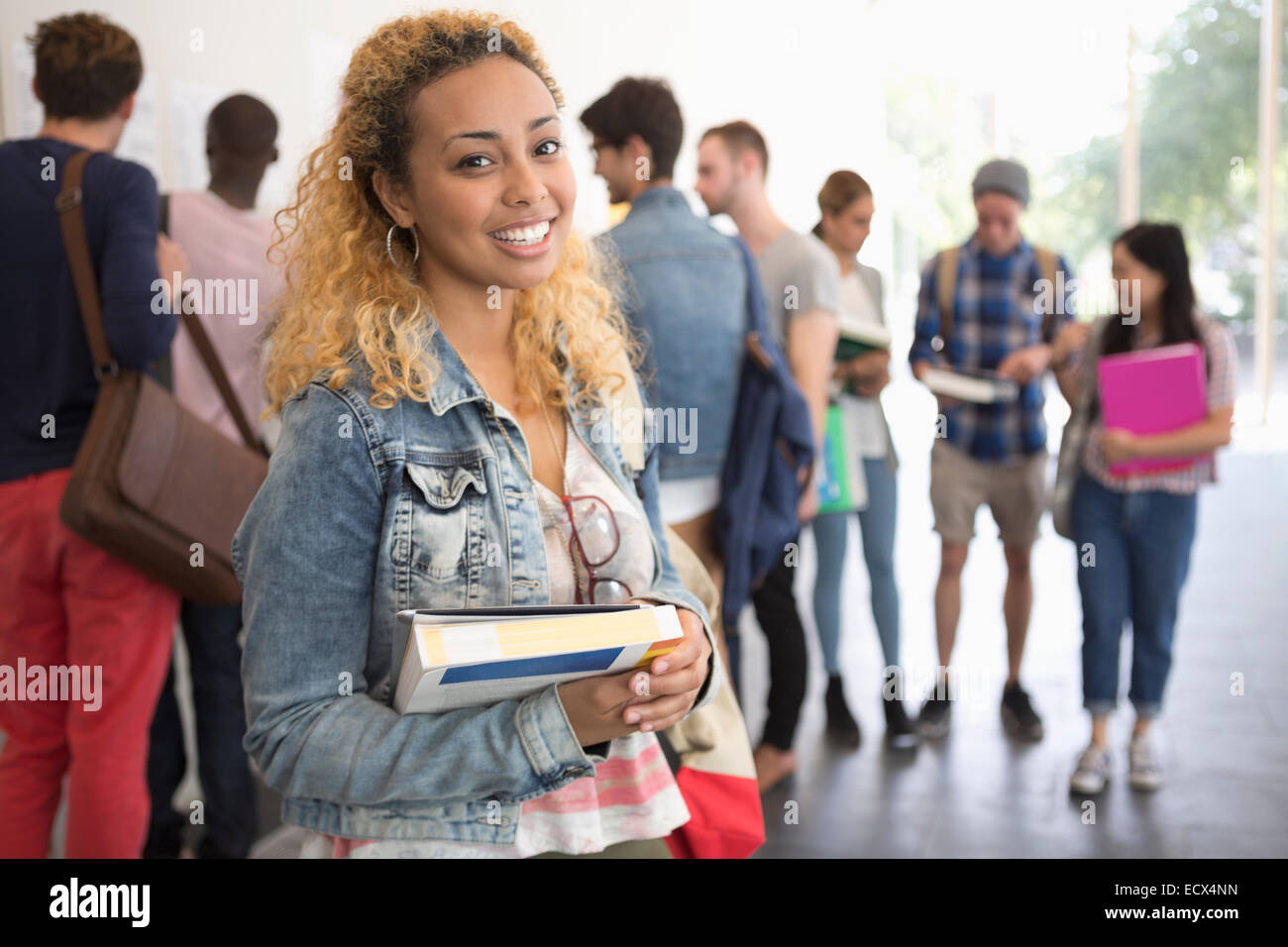 Smiling female student holding books and looking at camera Stock Photo ...