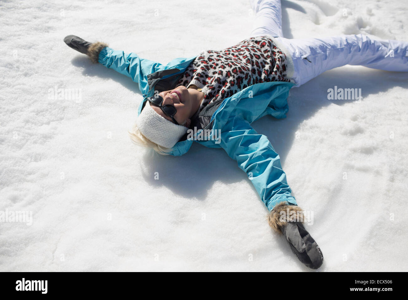 Happy woman making snow angels Stock Photo - Alamy