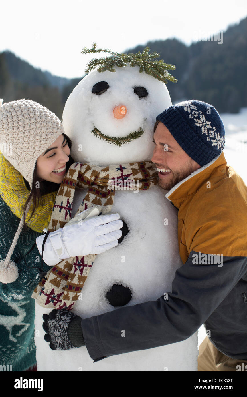 Couple hugging snowman Stock Photo - Alamy