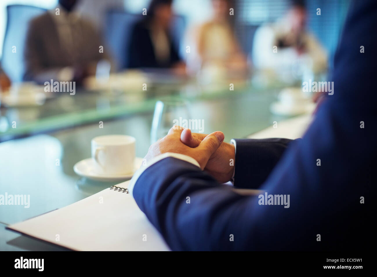 Businessman sitting at conference table in conference room with hands ...
