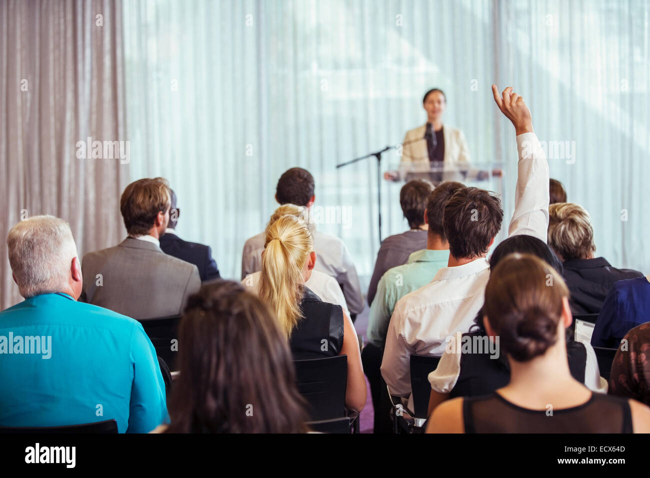 Businesswoman giving presentation in conference room, people raising ...