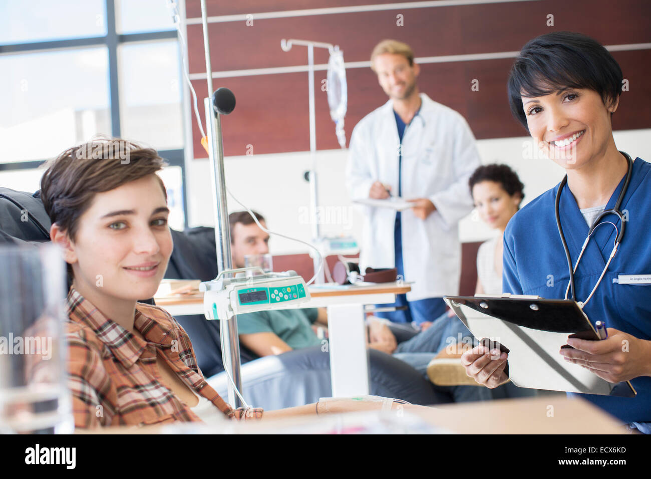 Smiling doctors checking with patients undergoing medical treatment in ...