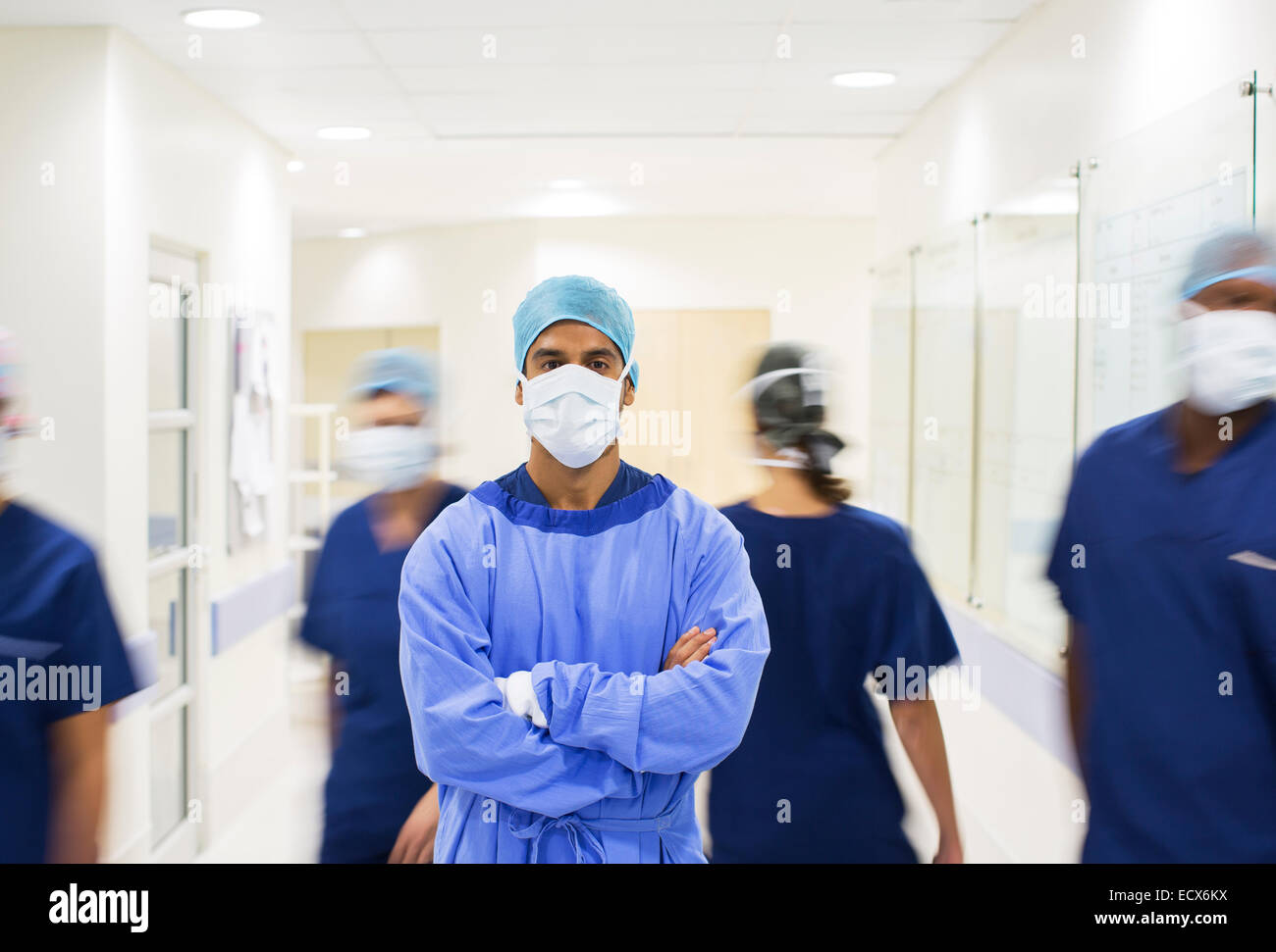 Surgeon with arms crossed, wearing scrubs standing in hospital corridor ...