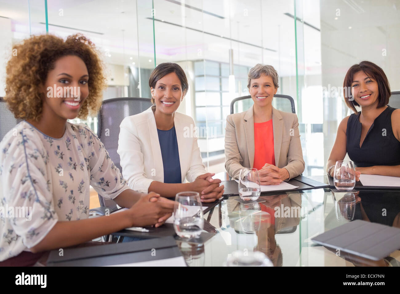 Portrait of four cheerful women sitting at conference table Stock Photo ...